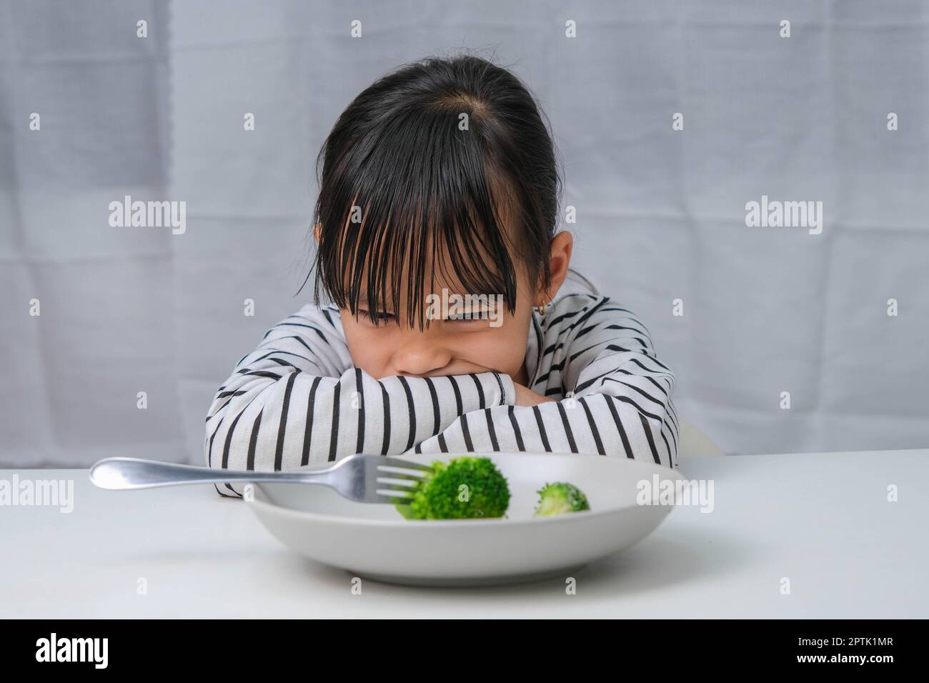 Children don't like to eat vegetables. Cute Asian girl refusing to eat ...