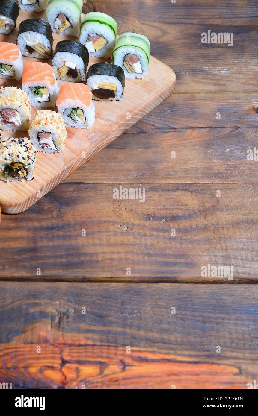 Sushi set of a number of rolls is located on a wooden cutting board on ...
