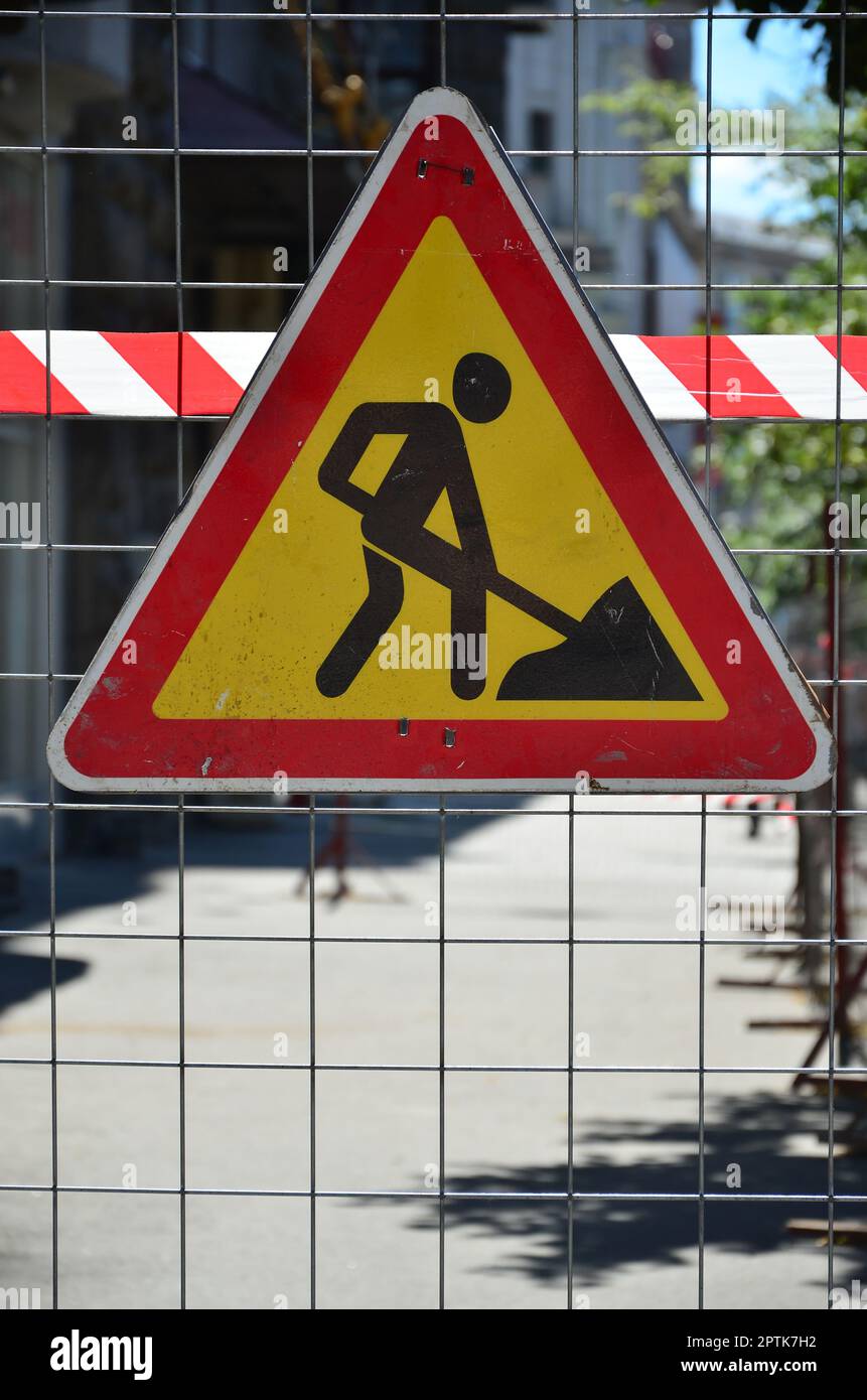 The warning sign "under construction" is attached to a metal mesh fence ...