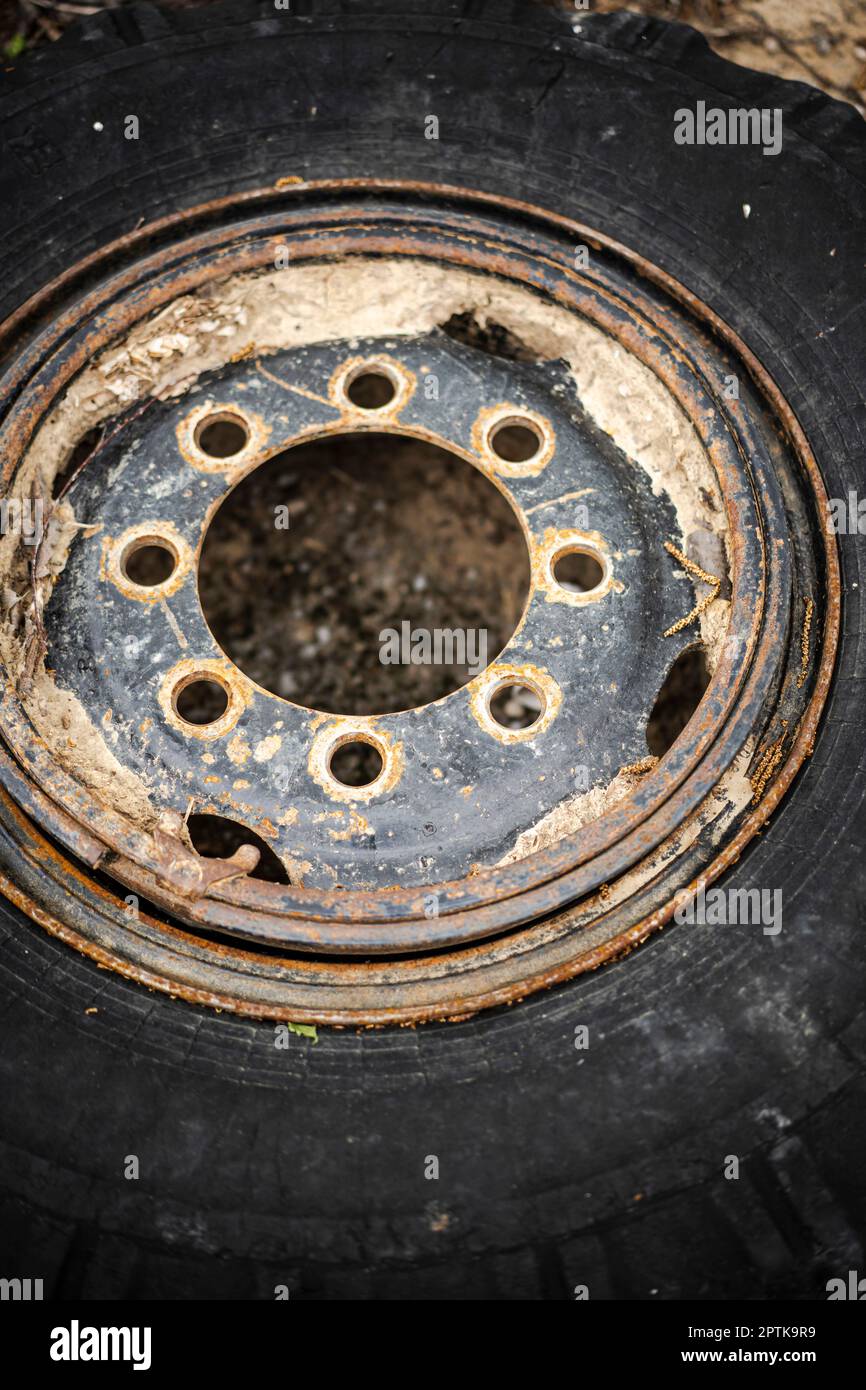 Detail of the used wheel of a truck, with a rusty rim and worn out tire ...
