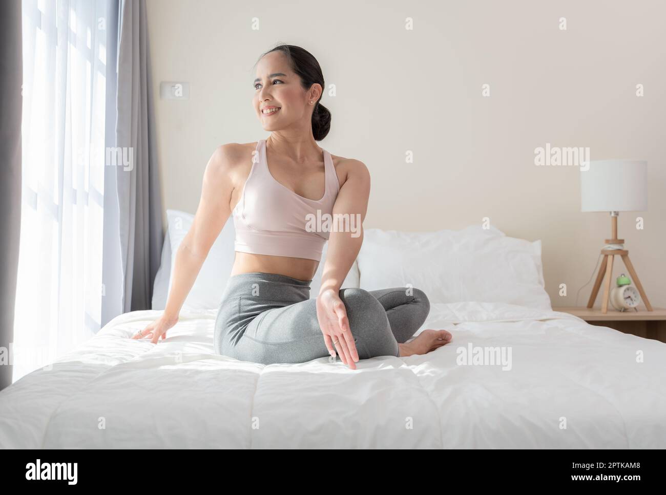 Asian woman doing yoga stretching exercise on bed at home. Morning ...
