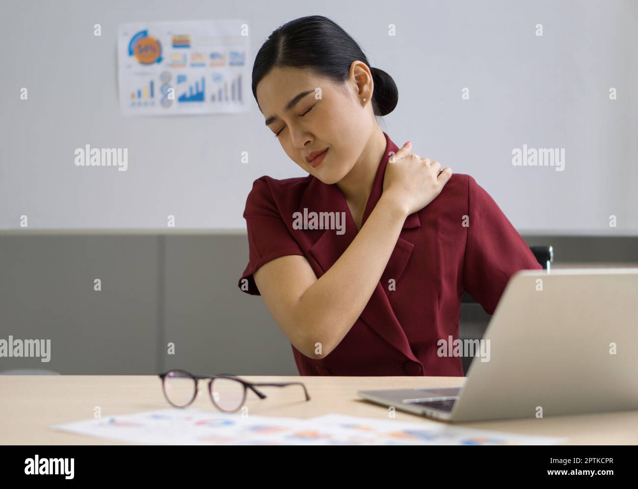 Young asian businesswoman grab the shoulder with her hand. To alleviate ...