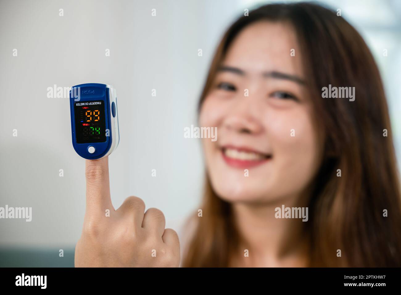 Asian young woman using medical oximeter equipment to measure pulse ...