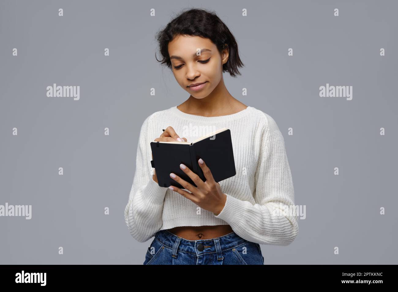 Concentrated young african woman standing against grey background and ...