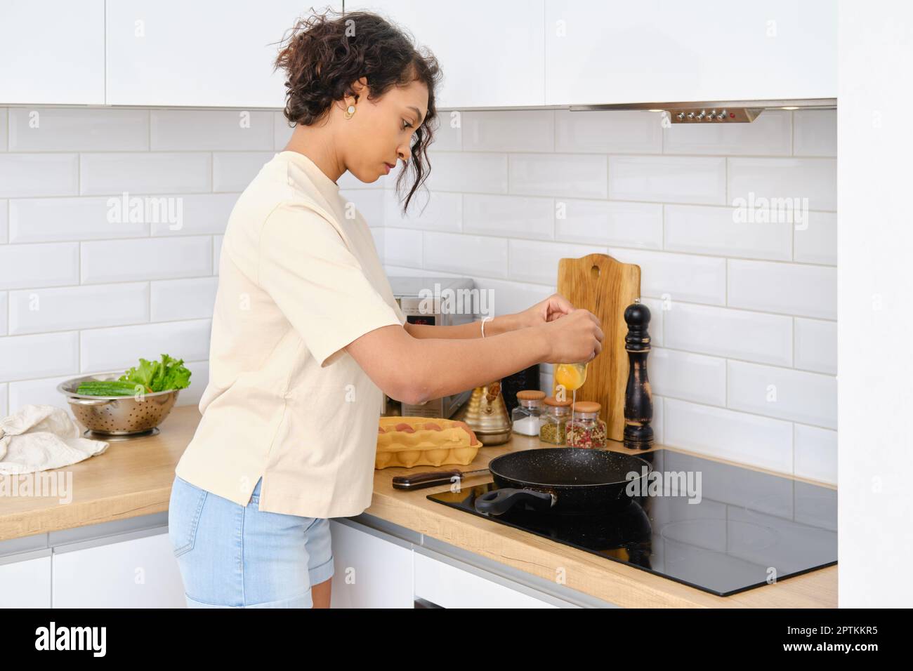 African american woman breaking egg in frying pan at home Stock Photo - Alamy