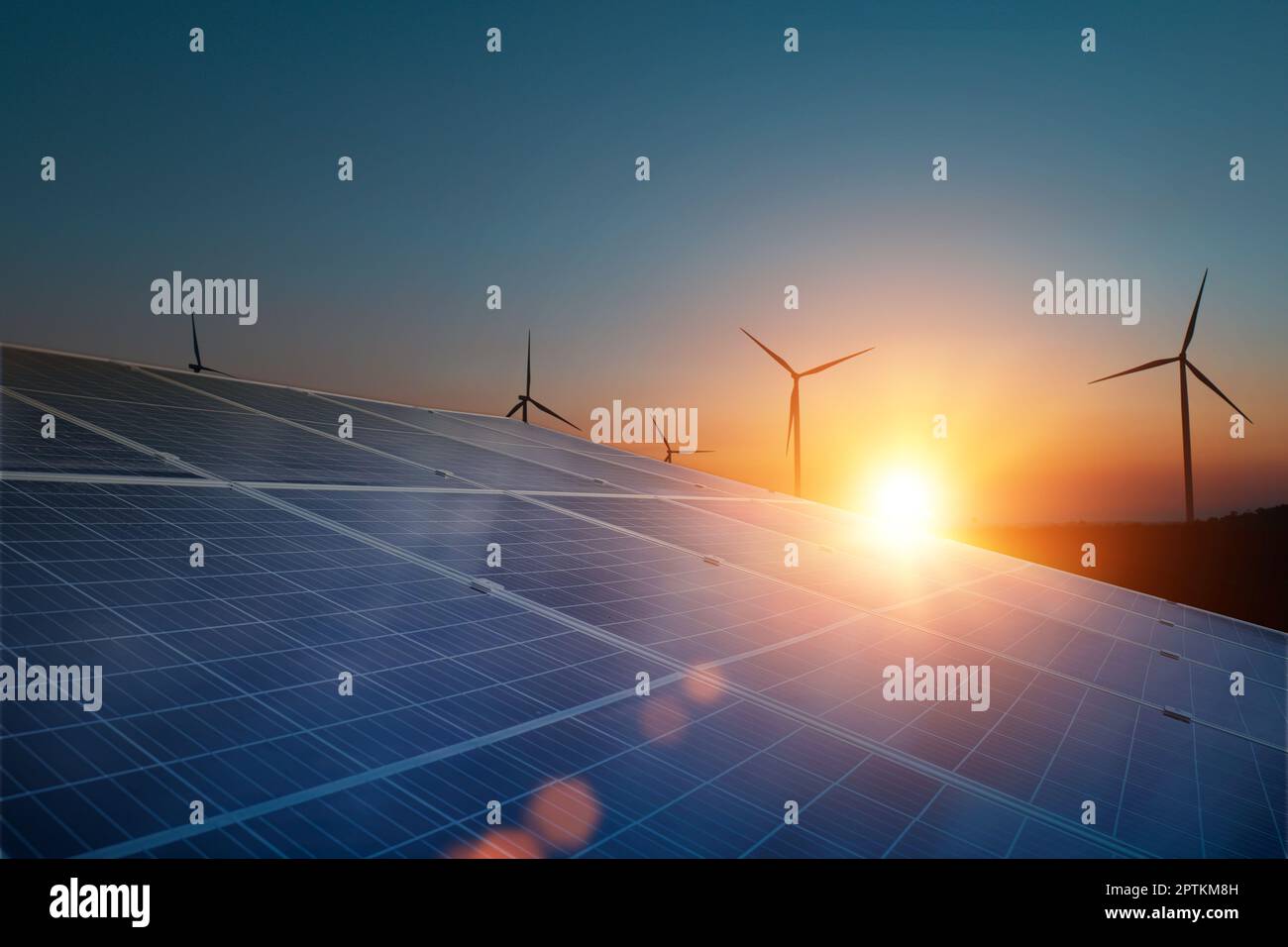 Solar panels with wind turbines against sunset sky background ...