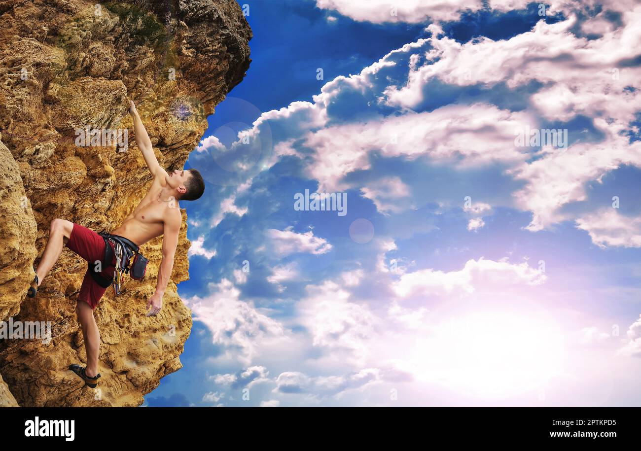Muscular man climbing on rock at sunset Stock Photo - Alamy