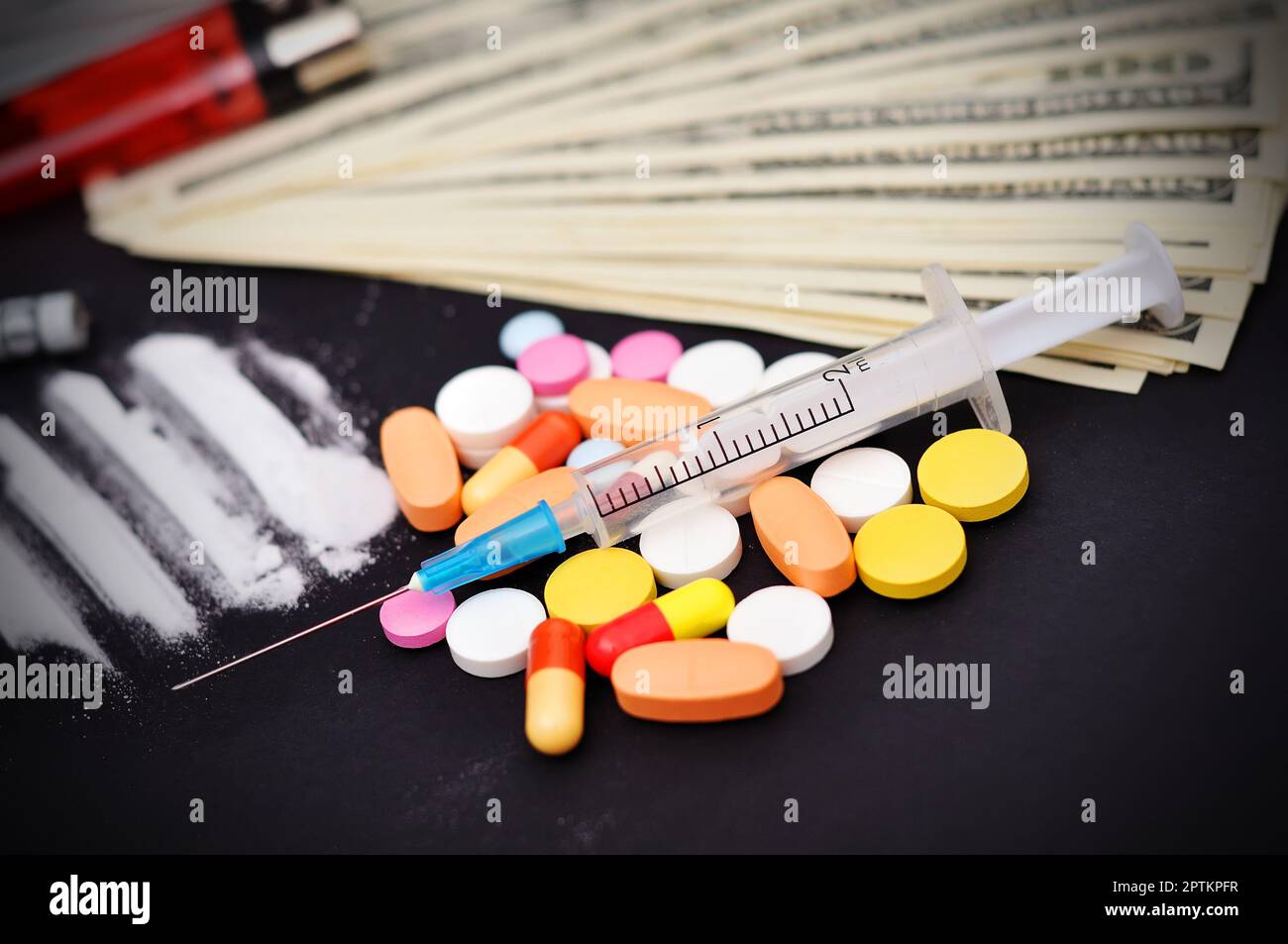 lines of cocaine, syringe, tablets and dollars on a black table Stock ...