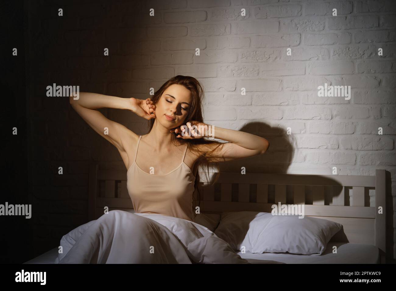 Cute sleepy woman stretches in bed after waking up early in the morning ...