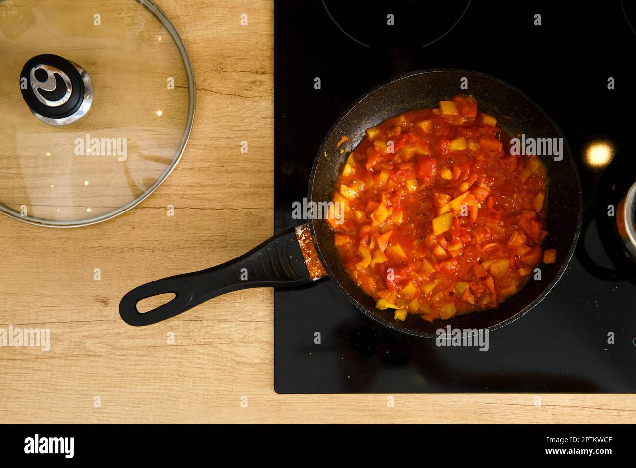 Overhead view of frying pan with tomato sauce on modern electric stove ...