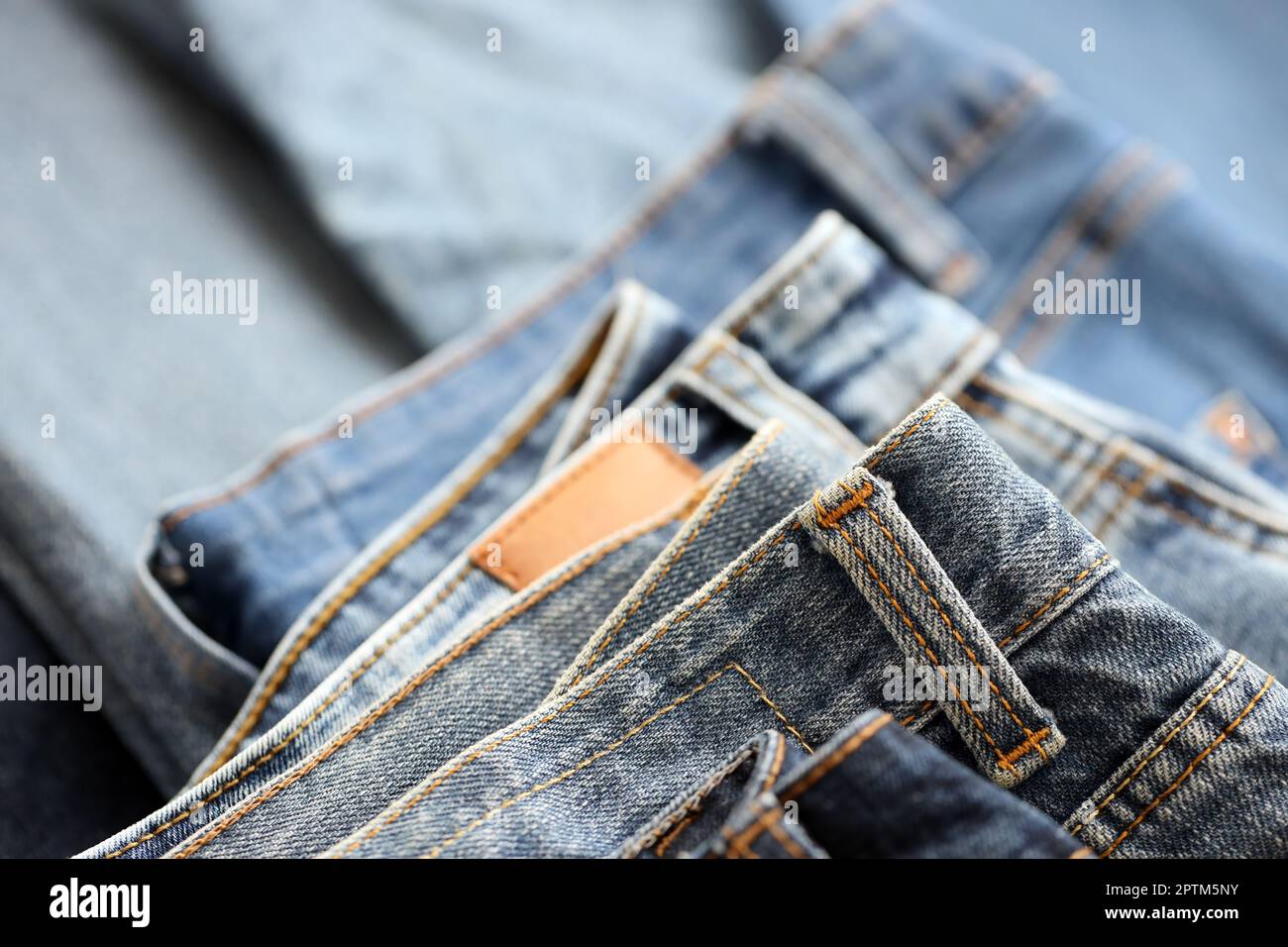 Many jeans in stack in wardrobe room. Row of pants denim jeans in ...