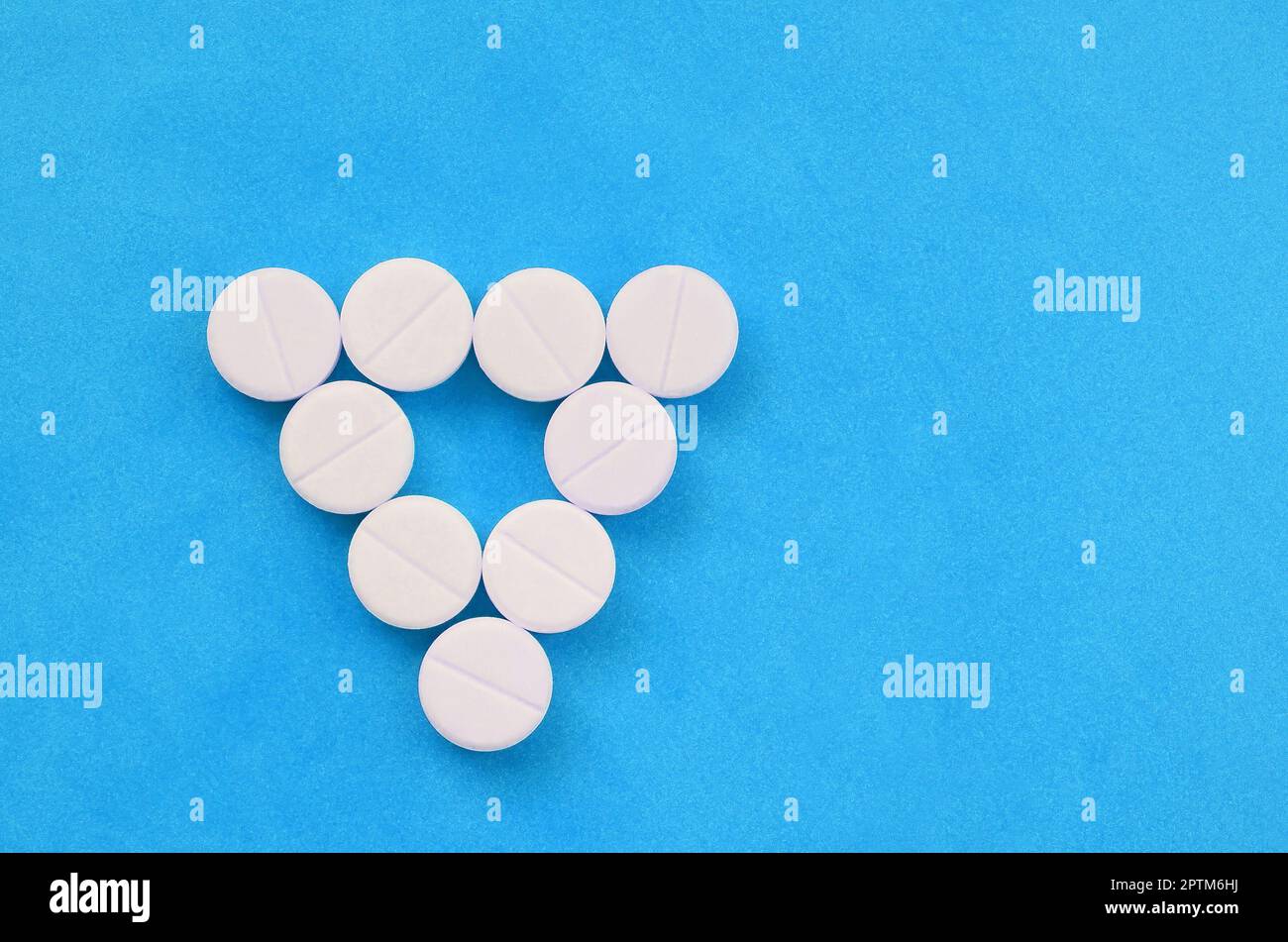 Several white tablets lie on a bright blue background in the form of an ...