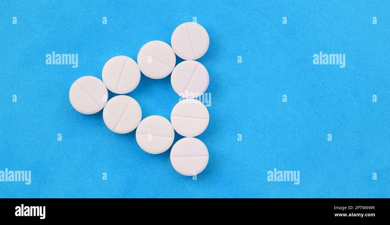 Several white tablets lie on a bright blue background in the form of an ...