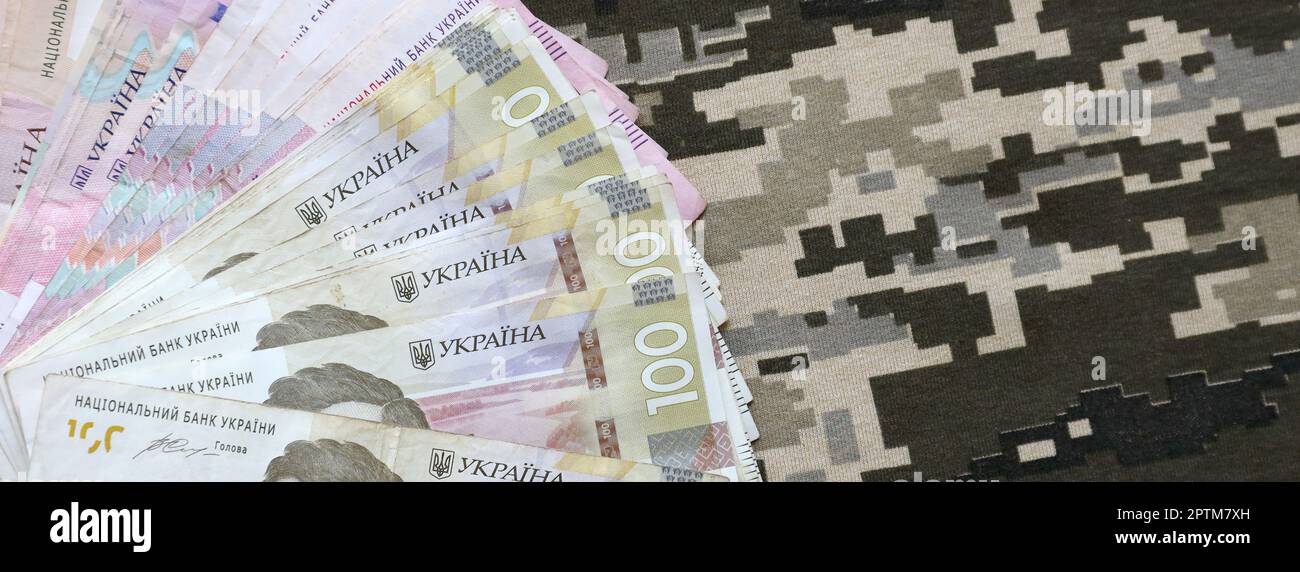 Ukrainian hryvnya bills on fabric with texture of Ukrainian military ...