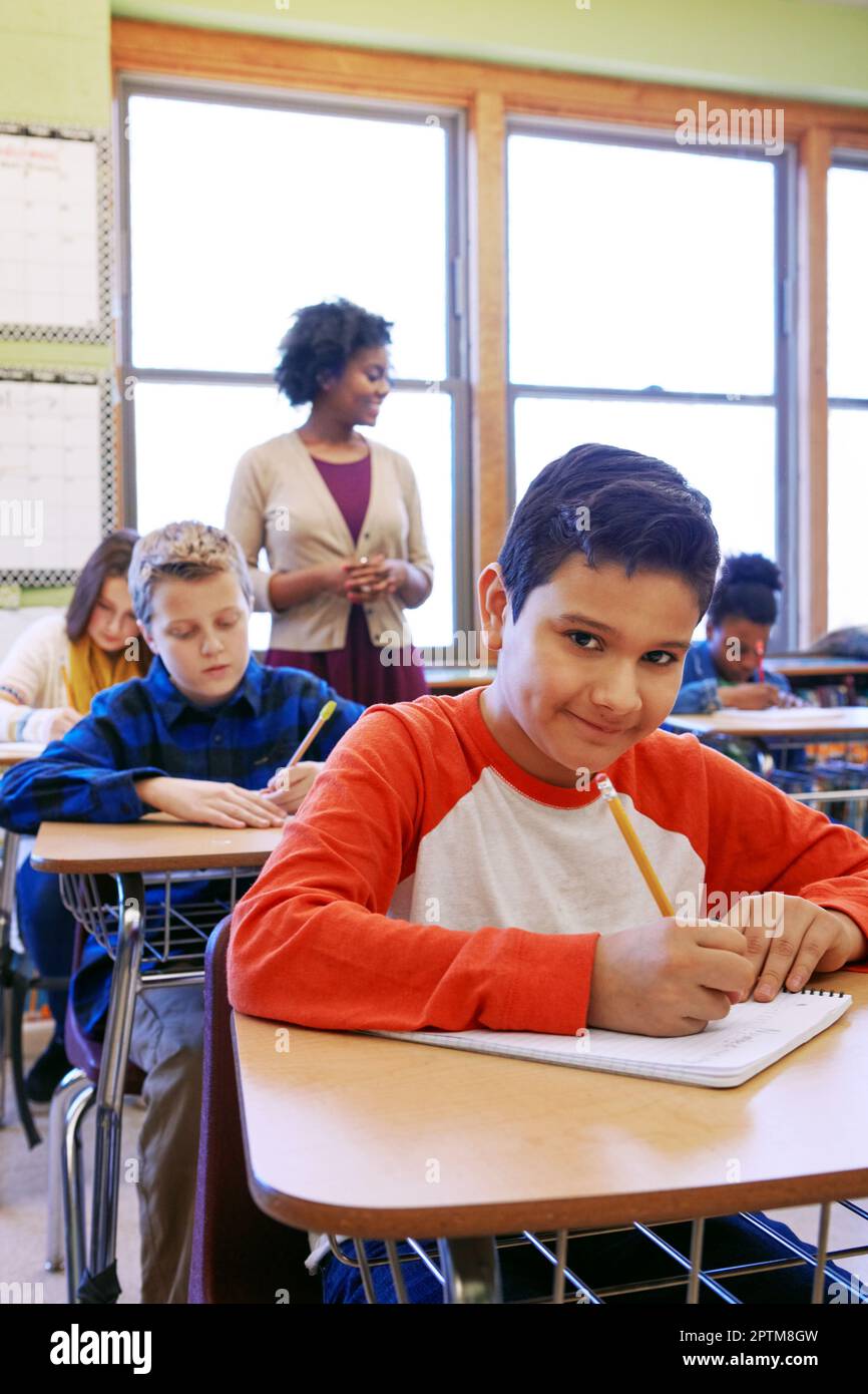 Hes got all the answers. a young boy sitting in class with his teacher ...