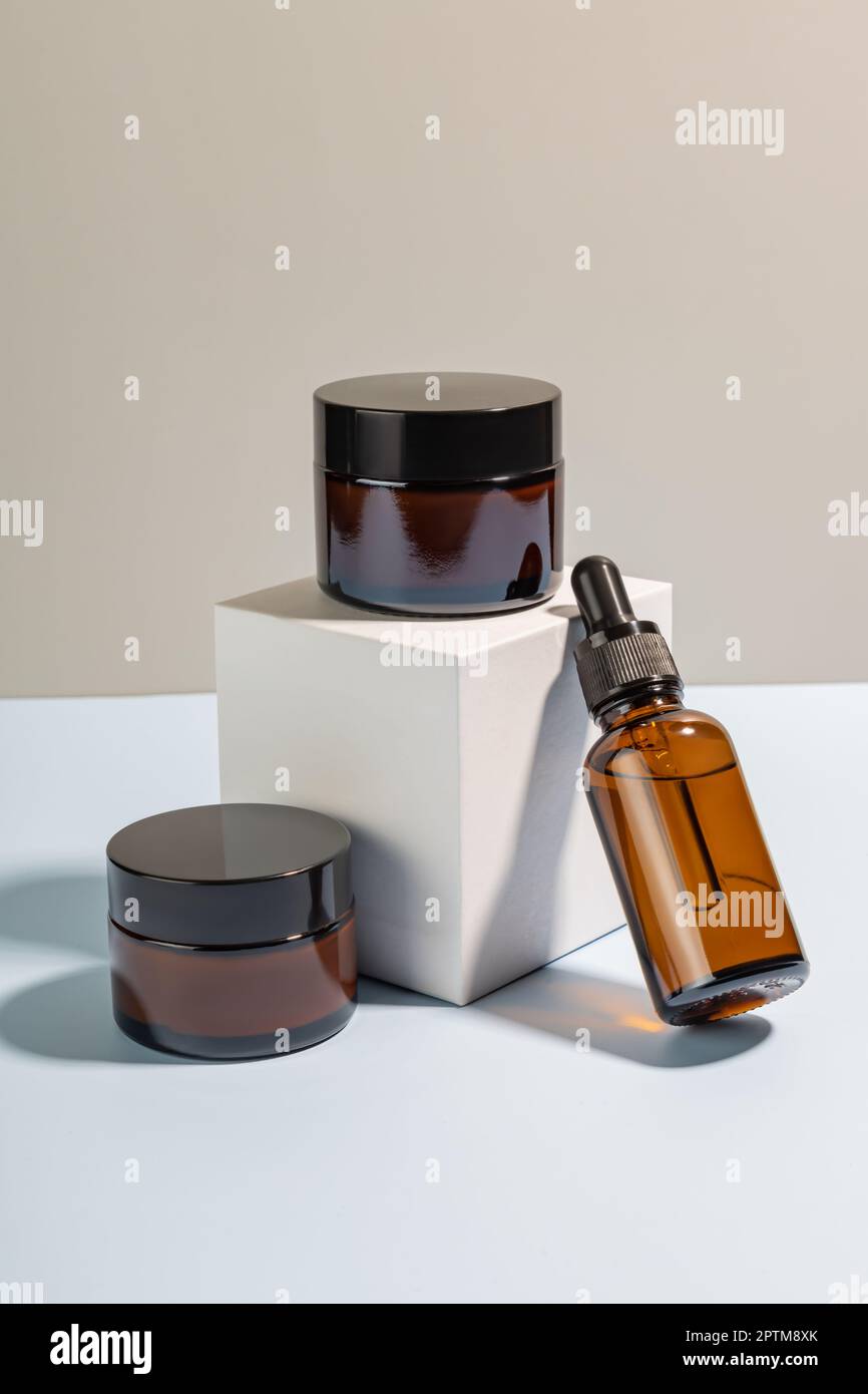 Beauty face serum in a glass dropper bottle and cream jars on white ...