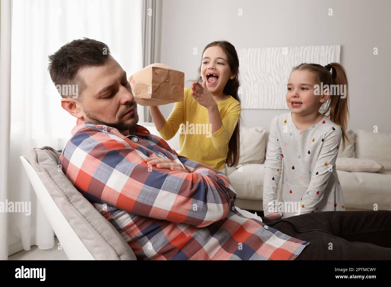 Cute little children popping paper near father while he sleeping at ...