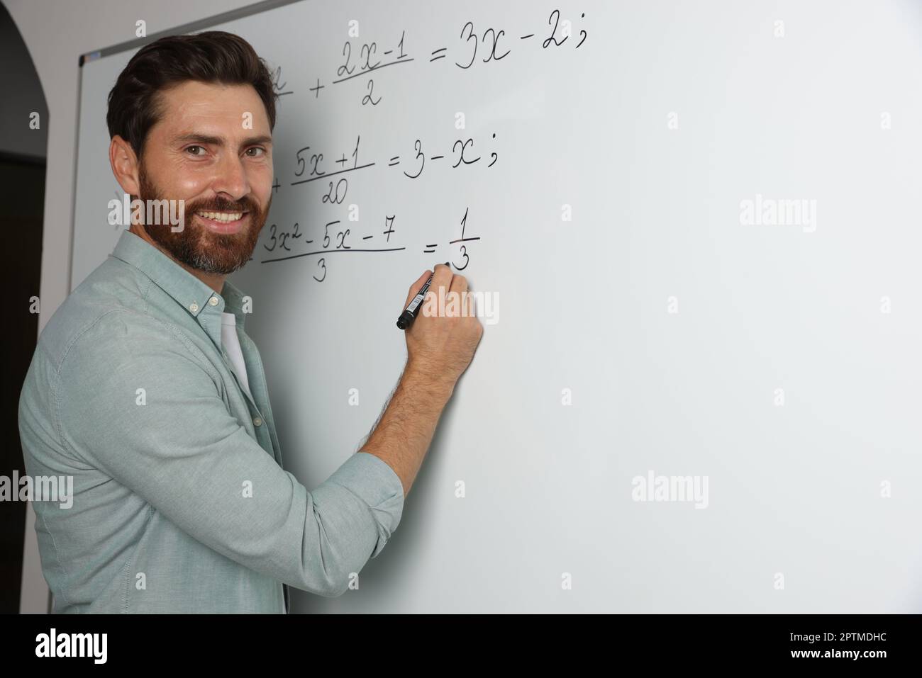 Happy teacher explaining mathematics at whiteboard in classroom Stock ...