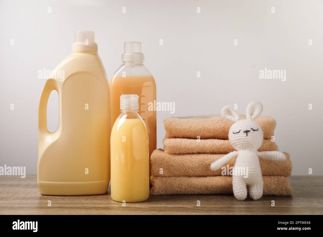 Bottles of laundry detergents, stacked fresh towels and knitted toy ...
