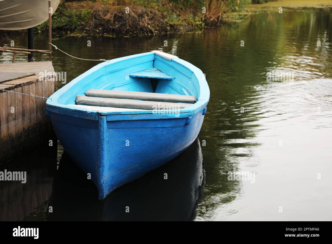 Light blue wooden boat on lake near pier Stock Photo - Alamy