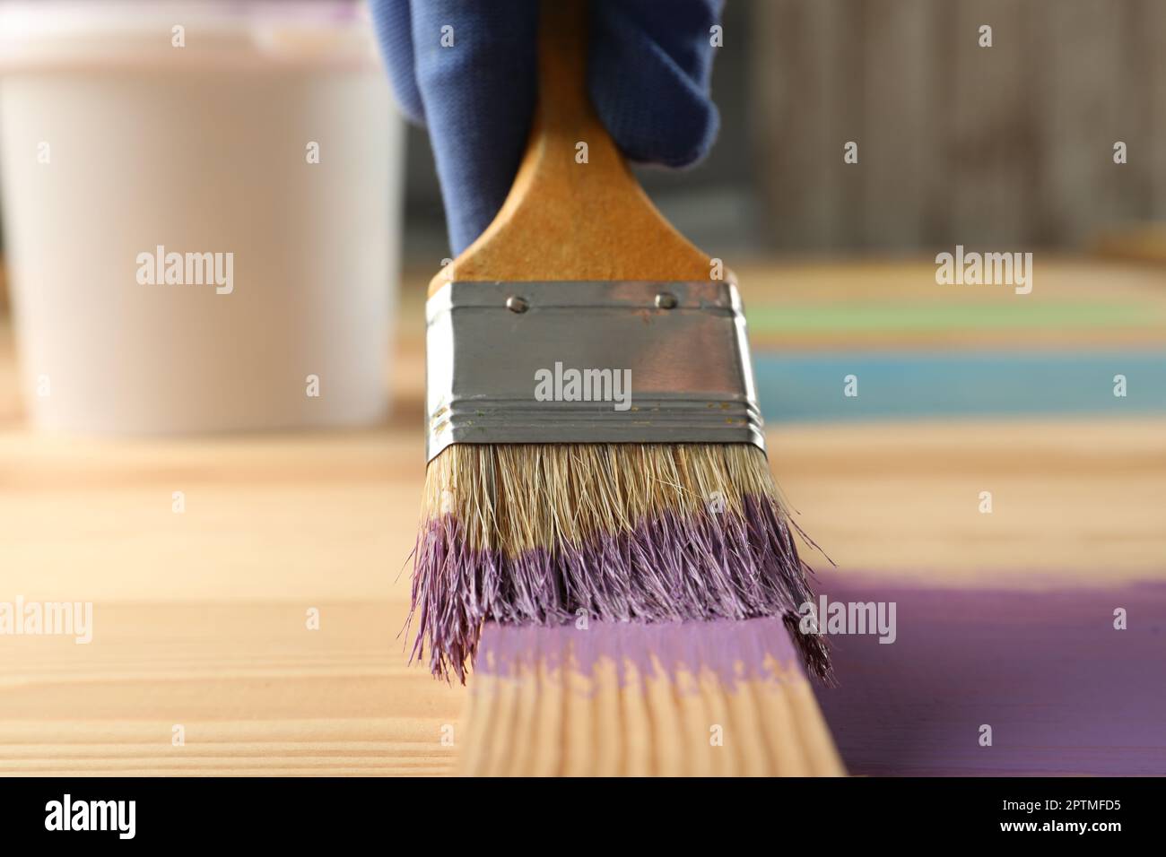 Worker applying violet paint onto wooden surface, closeup Stock Photo ...