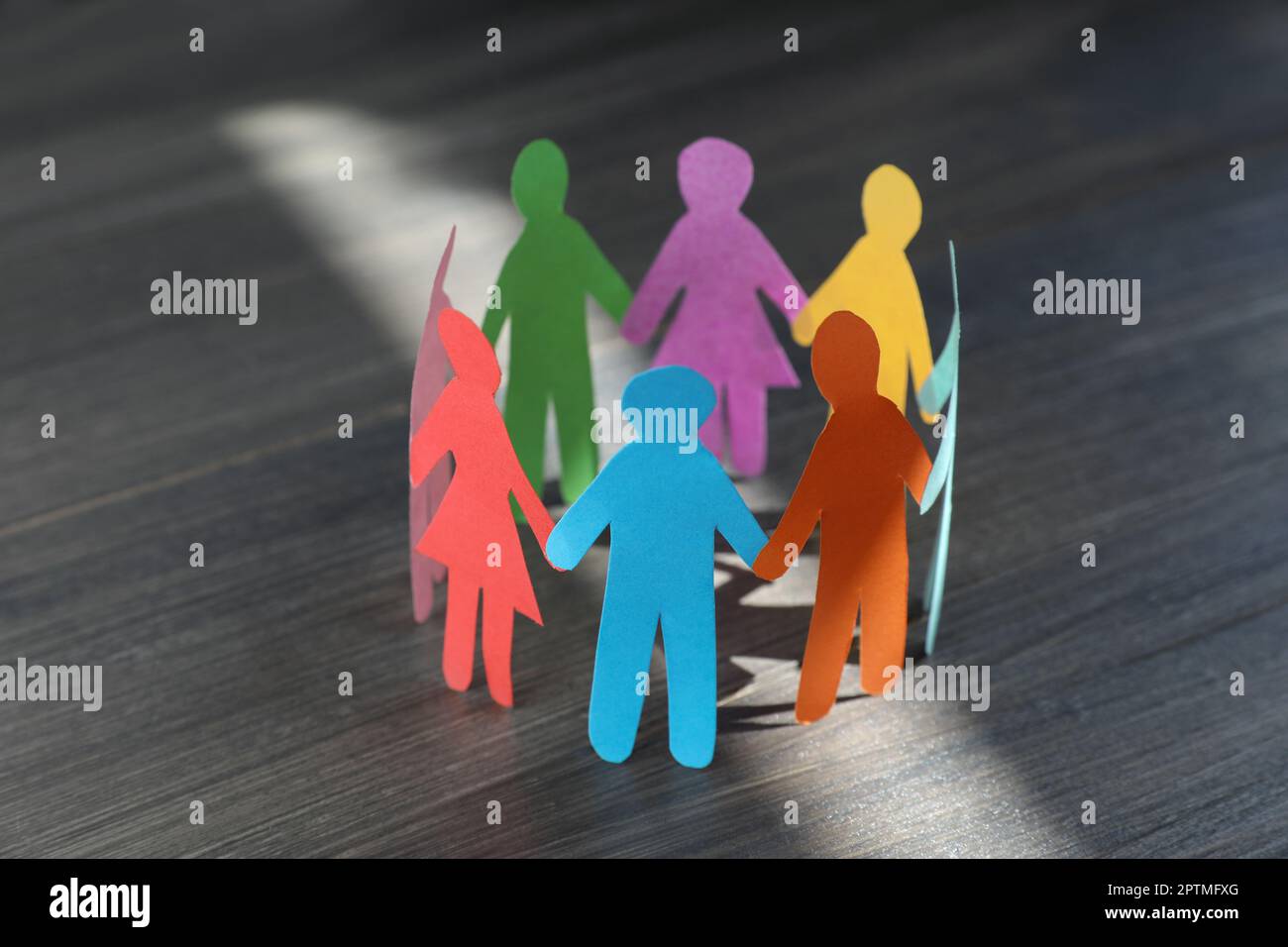 Paper human figures making circle on wooden table. Diversity and ...