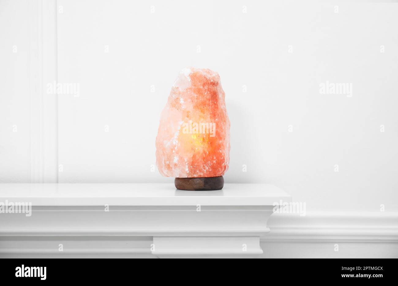 Himalayan salt lamp on console table near white wall Stock Photo - Alamy