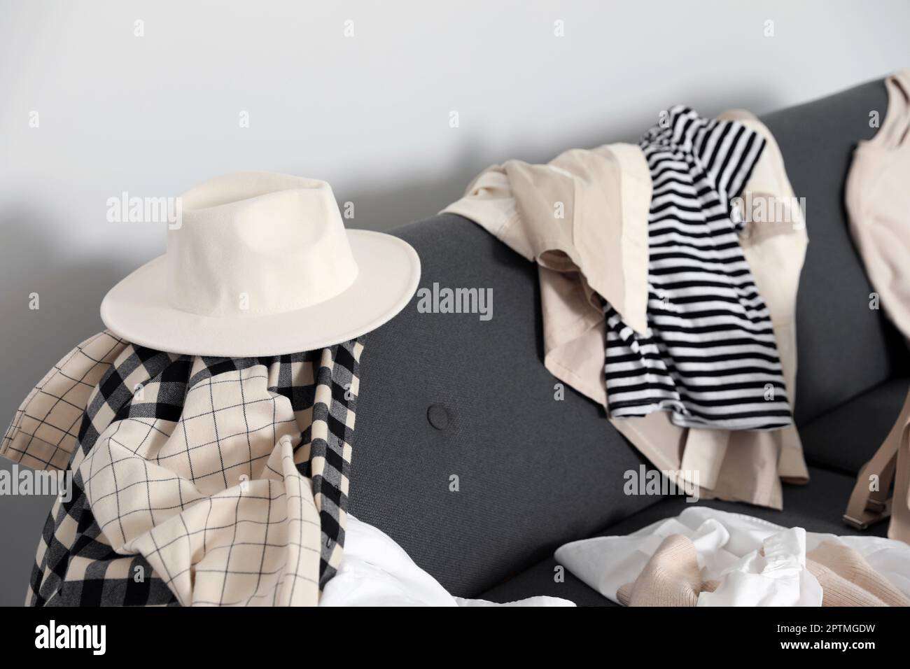 Messy pile of clothes on sofa in living room Stock Photo - Alamy