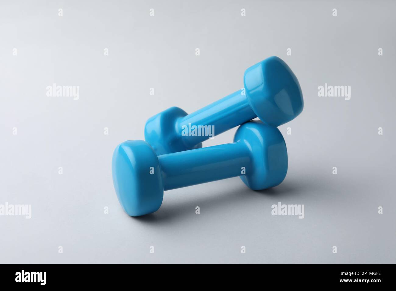 Two new blue vinyl dumbbells on light background Stock Photo - Alamy