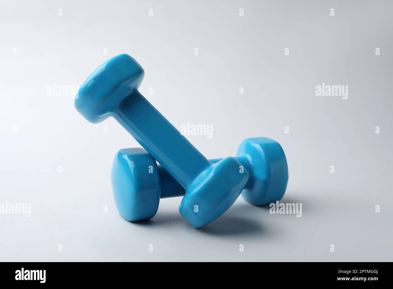 Two new blue vinyl dumbbells on light background Stock Photo - Alamy