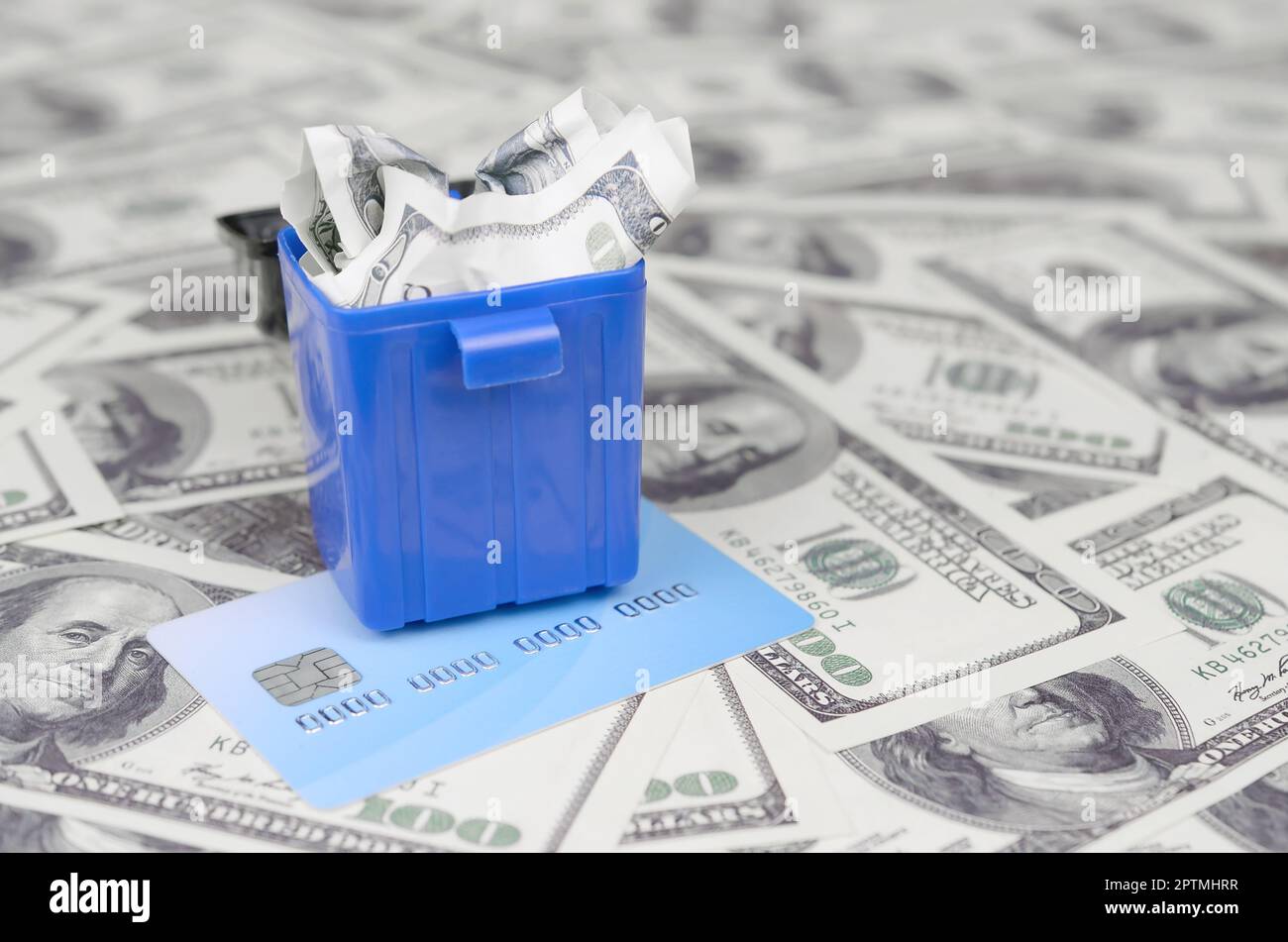 Dollar bills thrown into the trash and bank card. The concept of ...