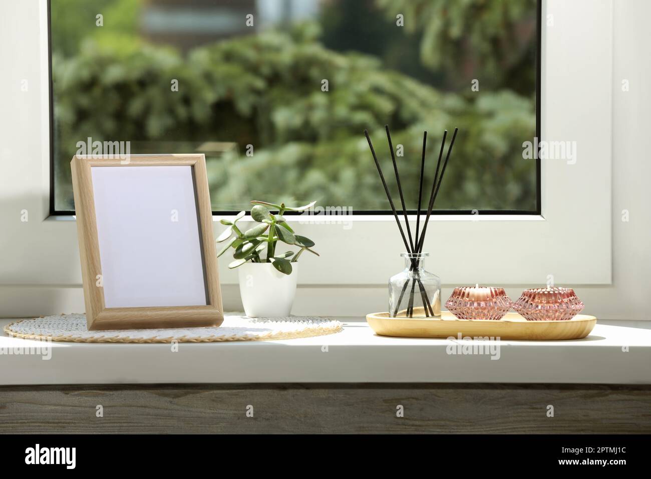 Blank photo frame with reed diffuser and home decor on white window ...