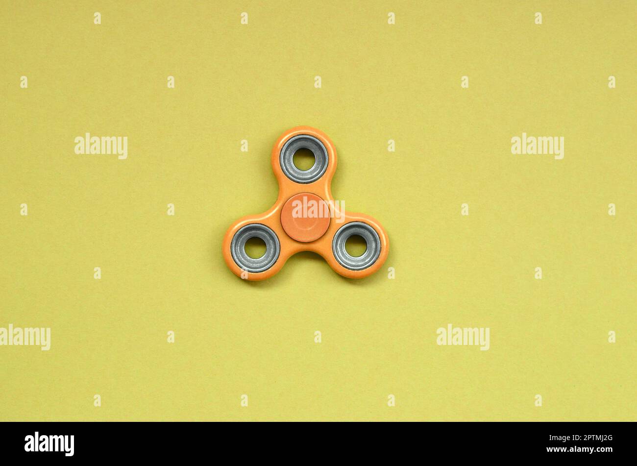 orange fidget spinner lies on texture background of fashion pastel ...