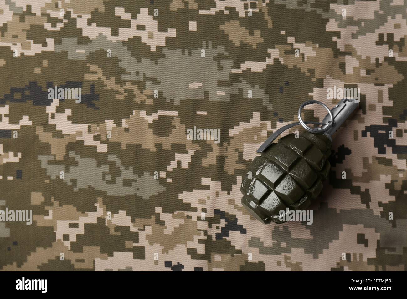 Hand grenade on digital camouflage fabric, top view. Space for text ...