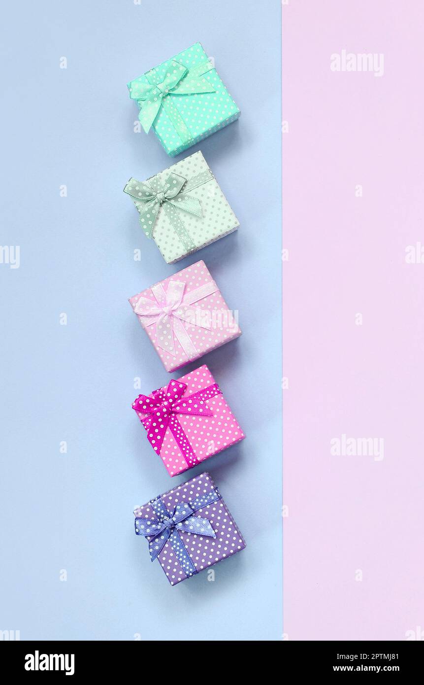 Small gift boxes of different colors with ribbons lies on a violet and ...