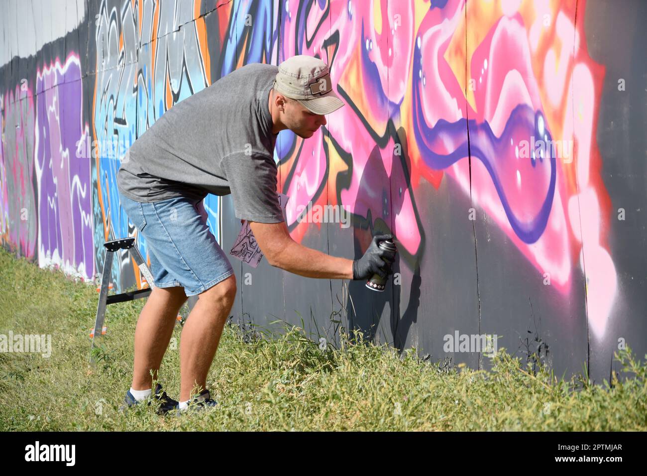 Young caucasian male graffiti artist drawing big street art painting in ...