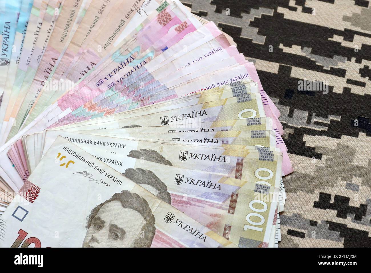 Ukrainian hryvnya bills on fabric with texture of Ukrainian military ...