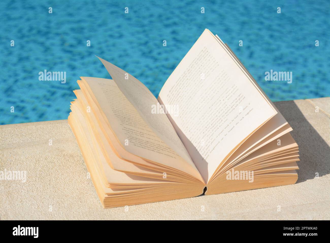 Open book on swimming pool edge during sunny day Stock Photo - Alamy