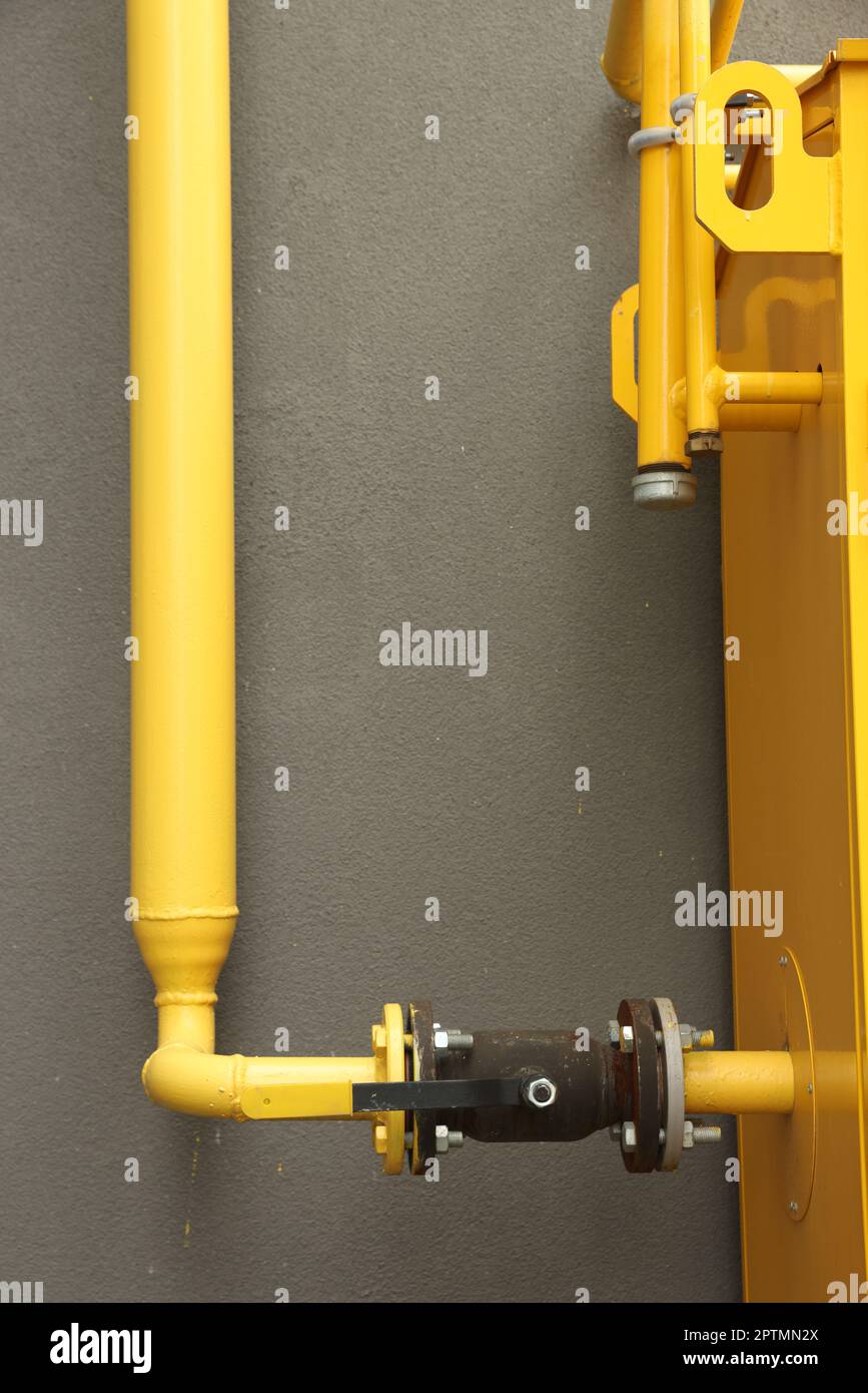 Yellow gas pipe near brown wall outdoors Stock Photo - Alamy