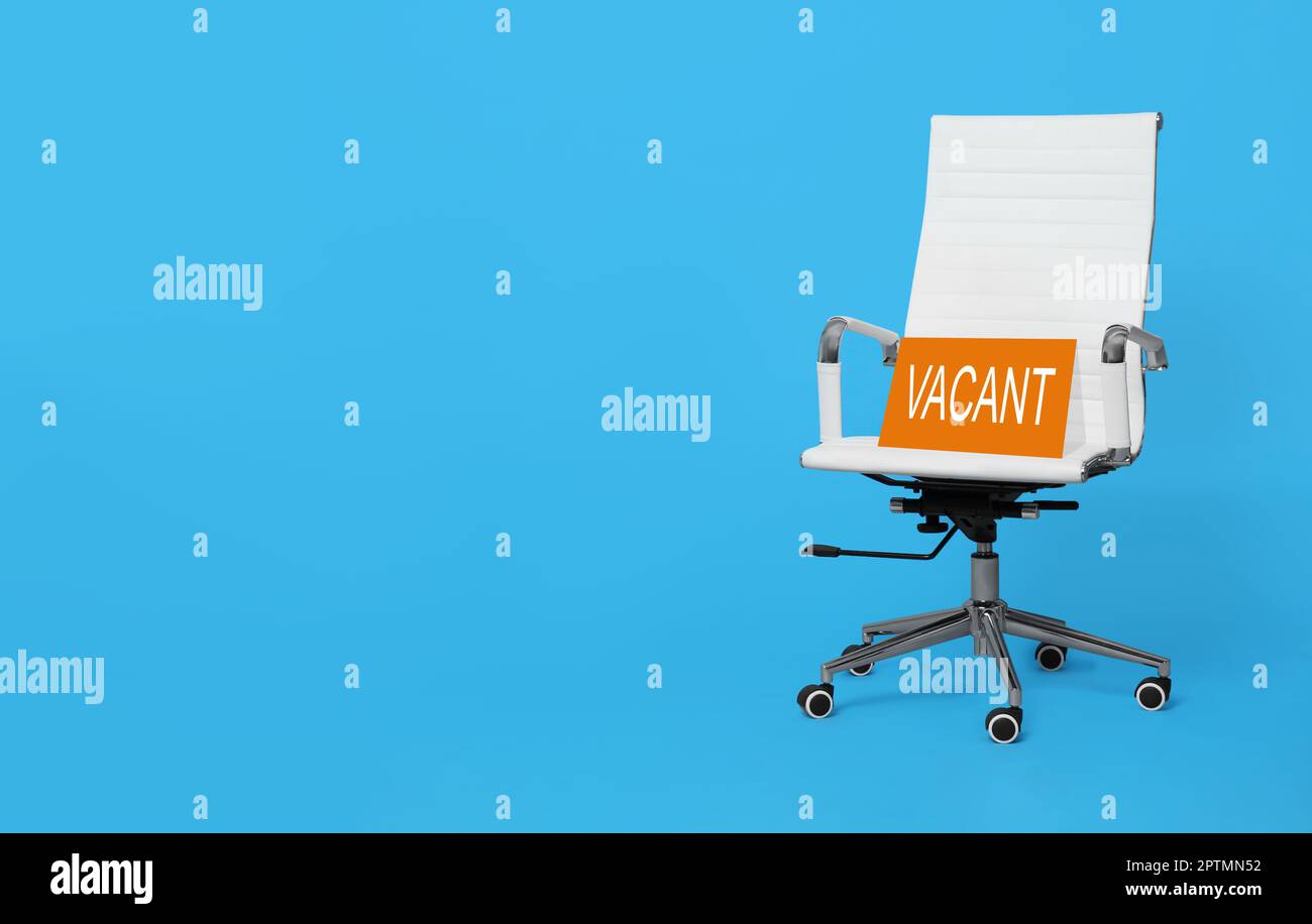 White office chair with sign VACANT on light blue background, space for ...