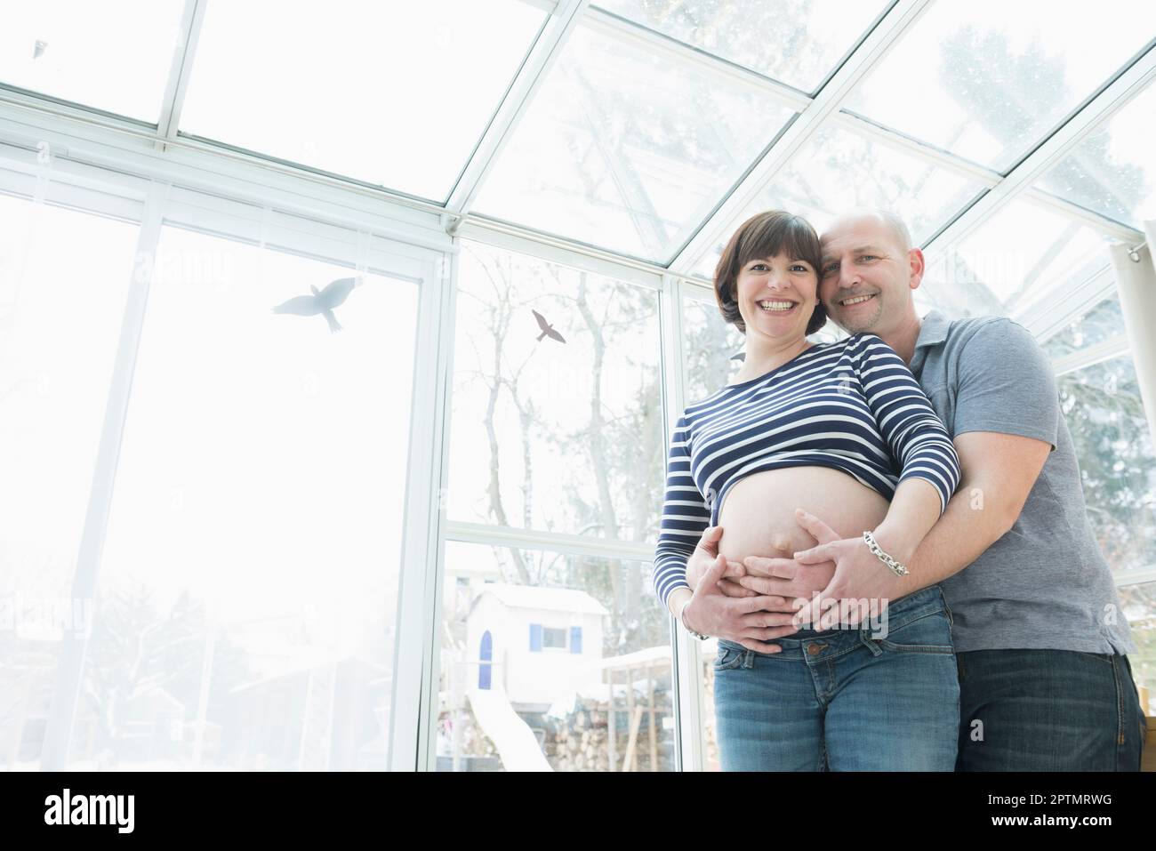 Low angle view of man holding belly of pregnant wife Stock Photo - Alamy