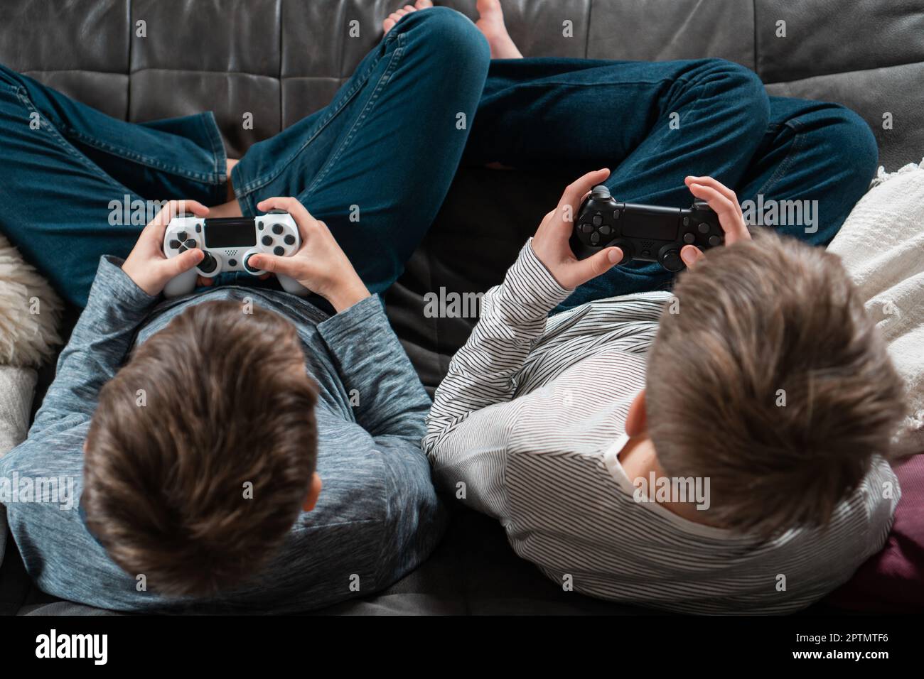 Guys sitting on sofa with game joysticks, from above view of crown and ...