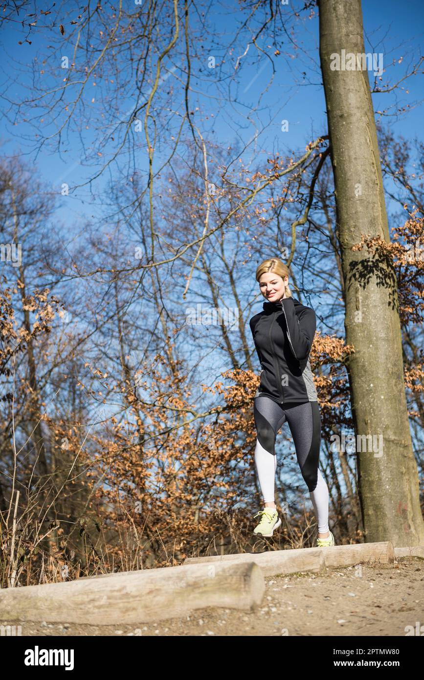 Woman doing exercise at obstacle course on fitness trail in forest ...