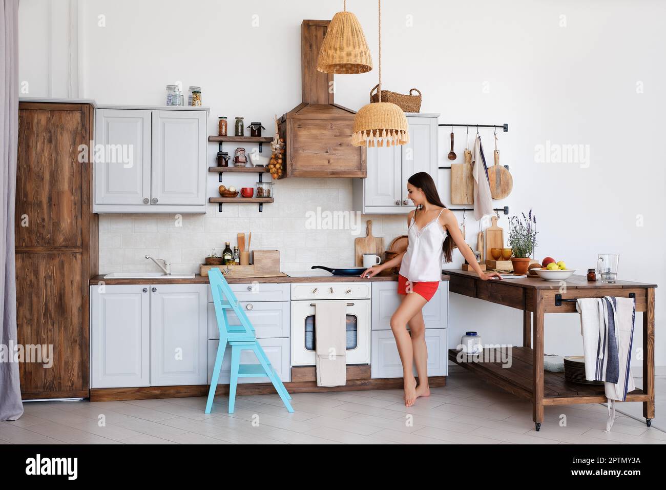 Lifestyle photo of cute girl standing by the stove in the kitchen ...