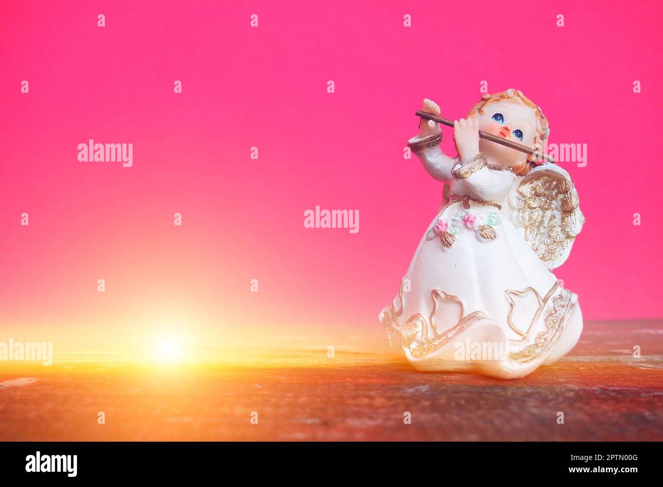 Guardian angel plays the flute. Figurine of a red-haired girl in a ...