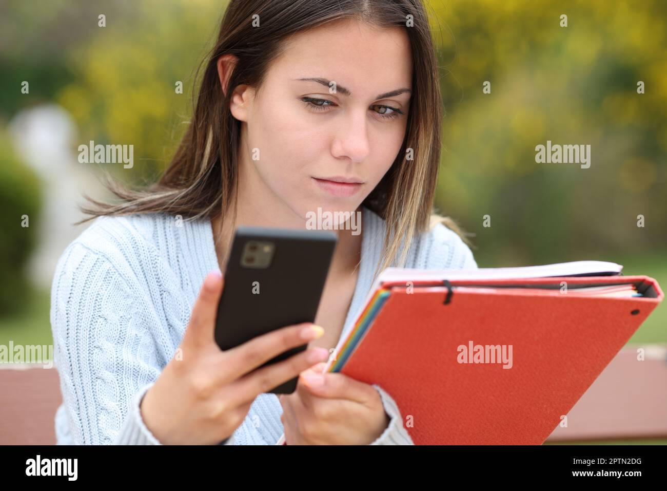 Student studying and checking phone in a park Stock Photo - Alamy