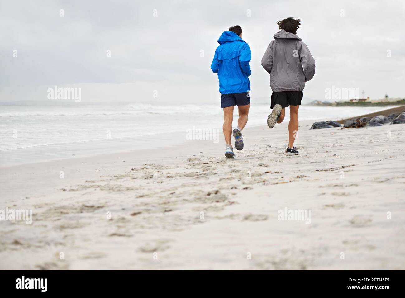 Getting fit with a friend. Rearview shot of two men jogging together ...