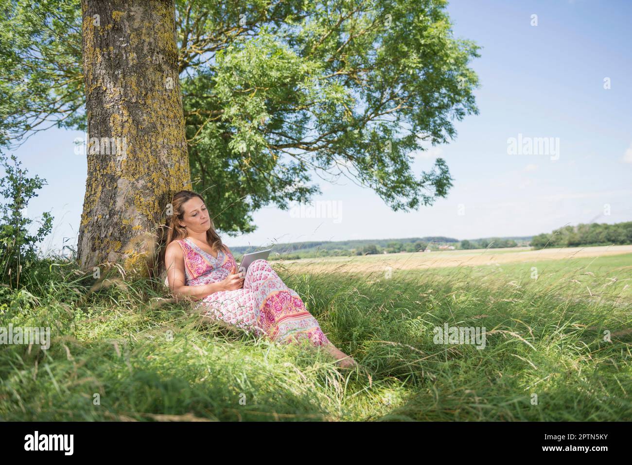 Woman sitting against tree trunk hi-res stock photography and images ...