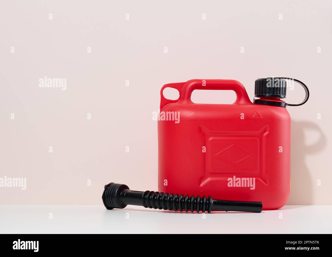 Red plastic canister for liquid fuels and lubricants on a beige ...