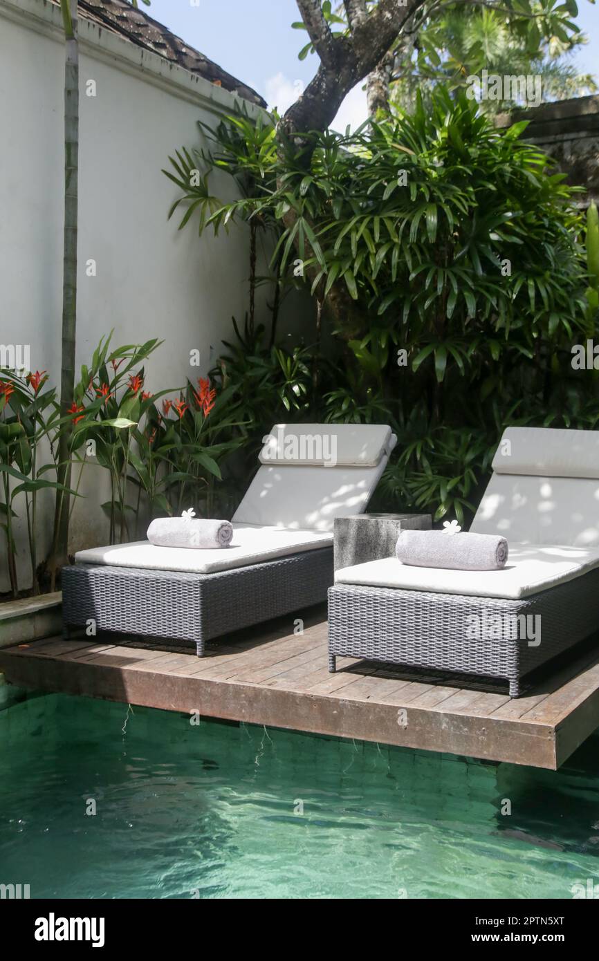 Two rattan lounge chairs by private swimming pool Stock Photo - Alamy